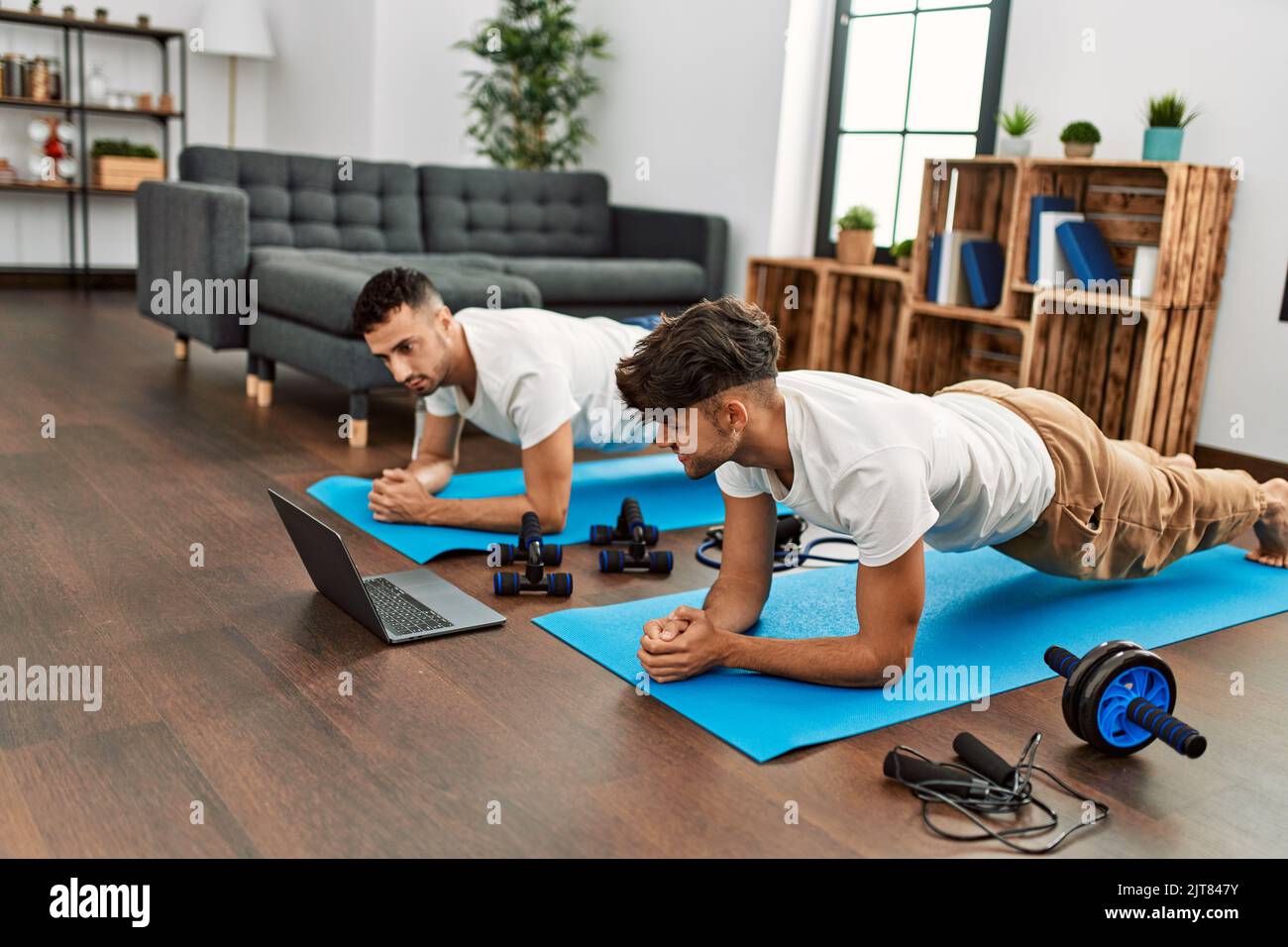 Two hispanic men couple smiling confident having online abs exercise ...