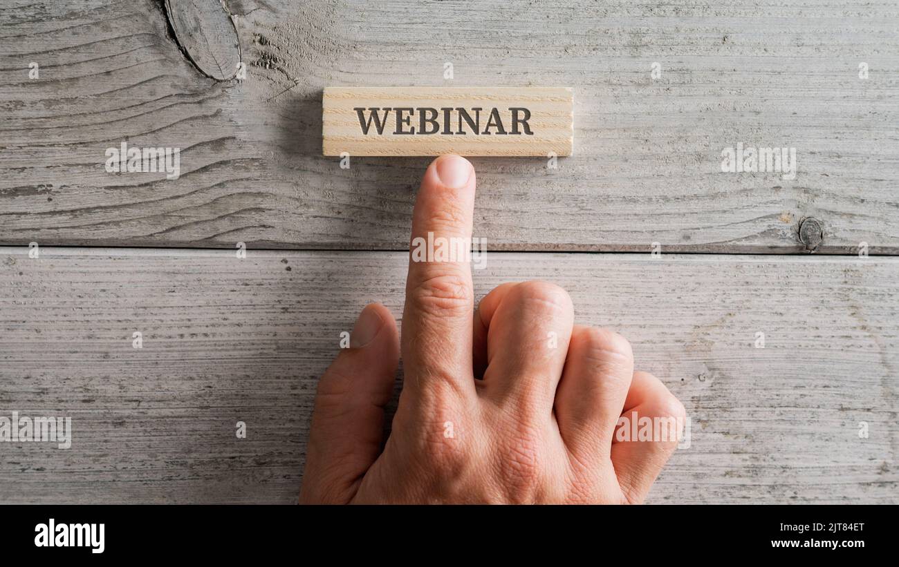 Male hand touching a button made of wooden peg with Webinar sign on it ...