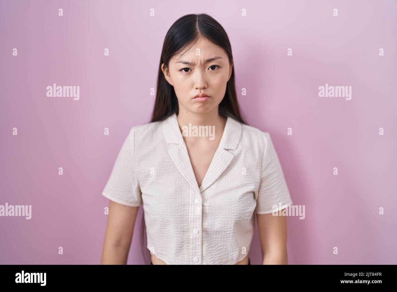 Chinese young woman standing over pink background depressed and worry ...