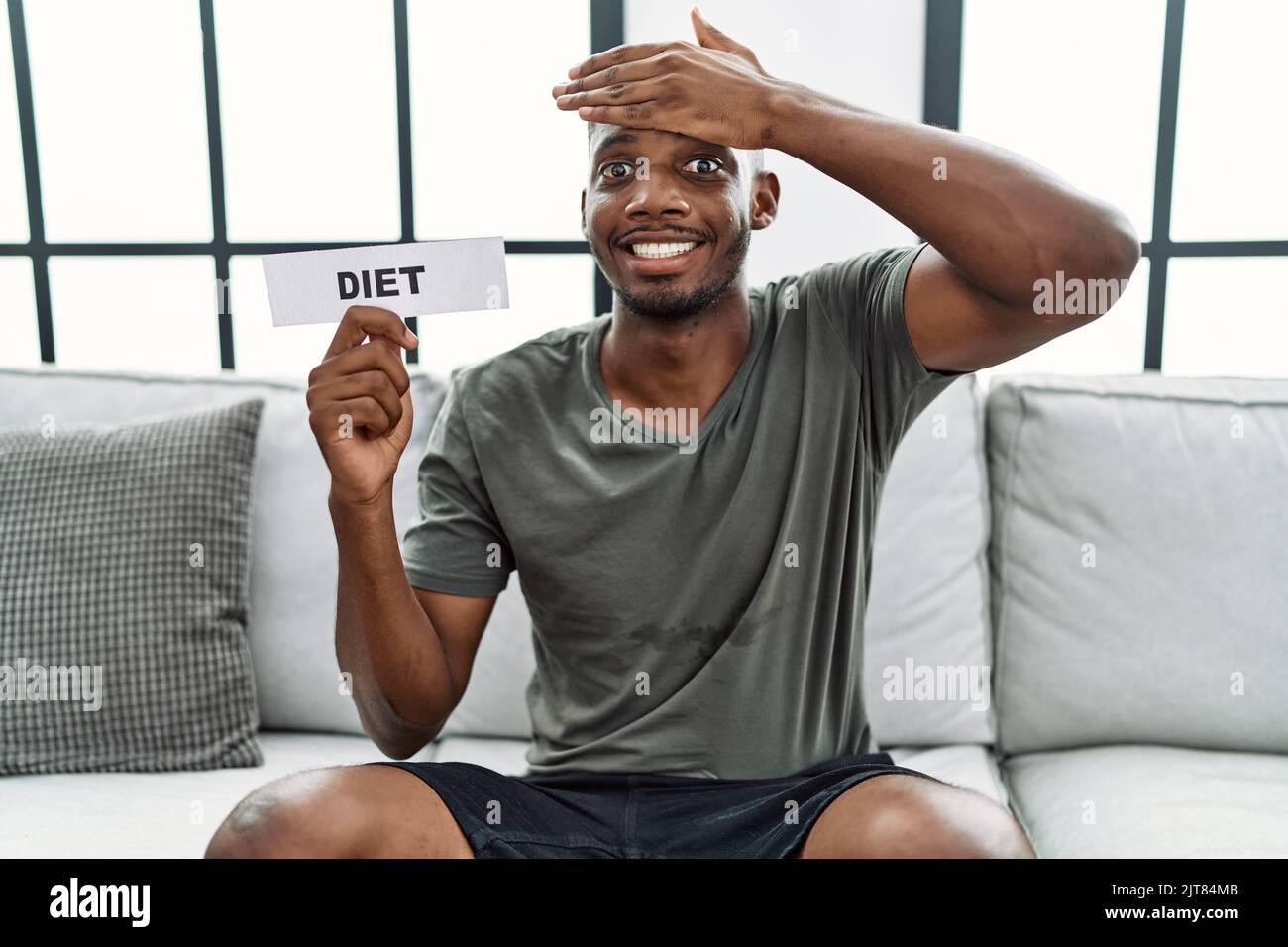 Young african american man holding diet banner sitting on the sofa at ...
