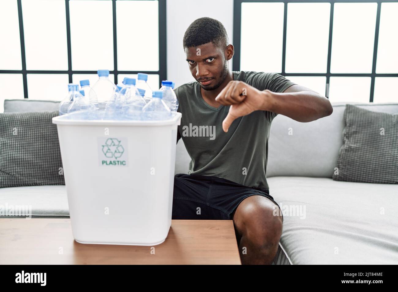 Young african american man holding wastebasket with recycling plastic ...