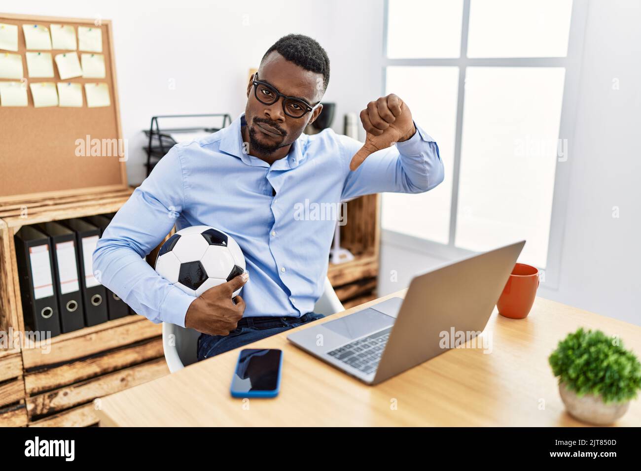 Young african man football hooligan cheering game at the office with ...