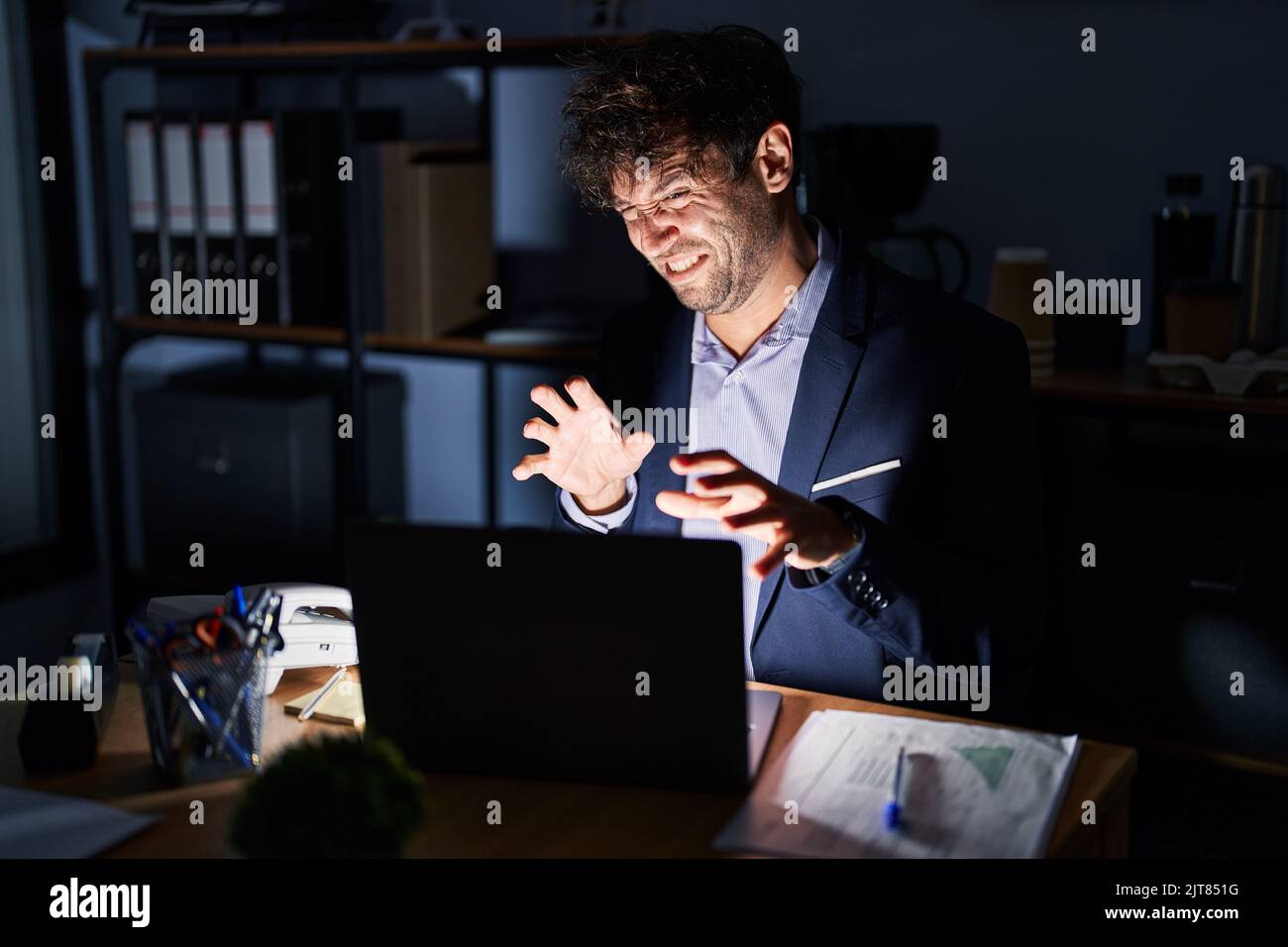Hispanic young man working at the office at night disgusted expression ...