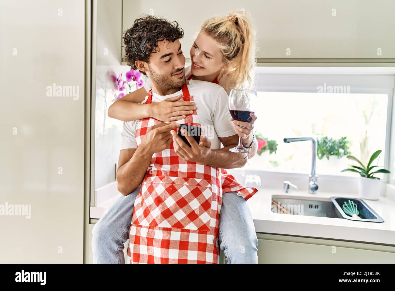 Young couple smiling happy hugging and sitting on counter. Drinking red ...