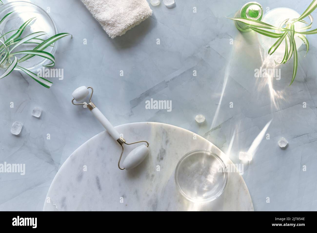 Home made moisturizer and green jade stone face roller on off white ...