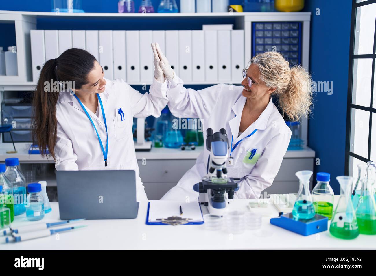 Two women scientists high five with hands raised up working at ...
