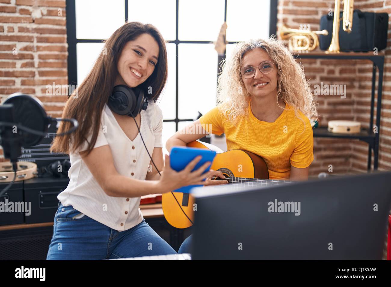 Two women musicians playing classical guitar looking touchpad at music ...