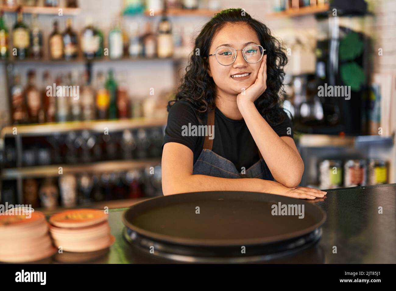 Young chinese woman waitress smiling confident leaning on counter at ...