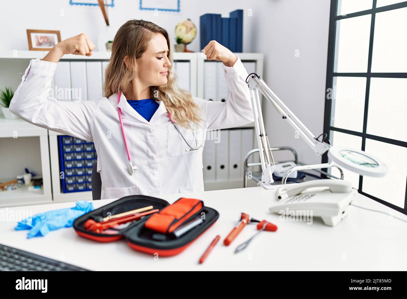 Young beautiful doctor woman with reflex hammer and medical instruments ...
