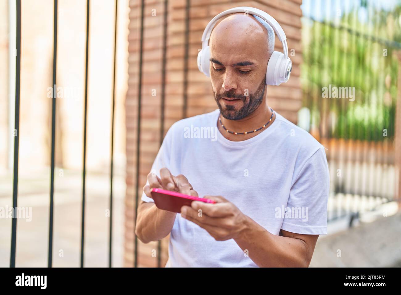 Young bald man playing video game at street Stock Photo - Alamy