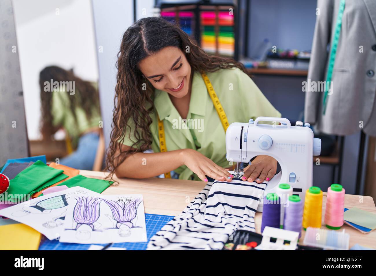 Young beautiful hispanic woman tailor smiling confident using sewing ...