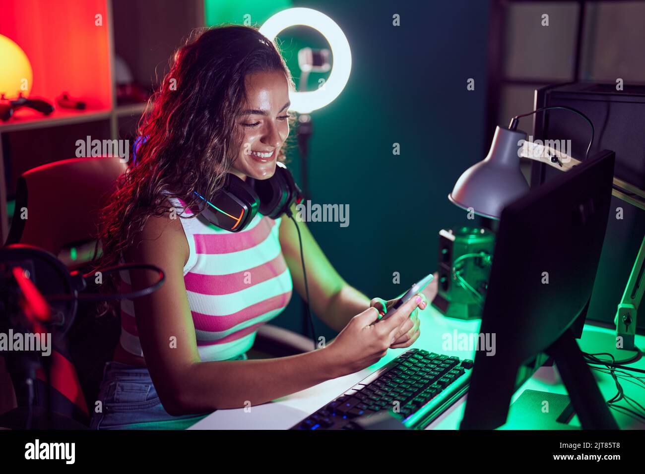Young beautiful hispanic woman streamer using computer and smartphone ...