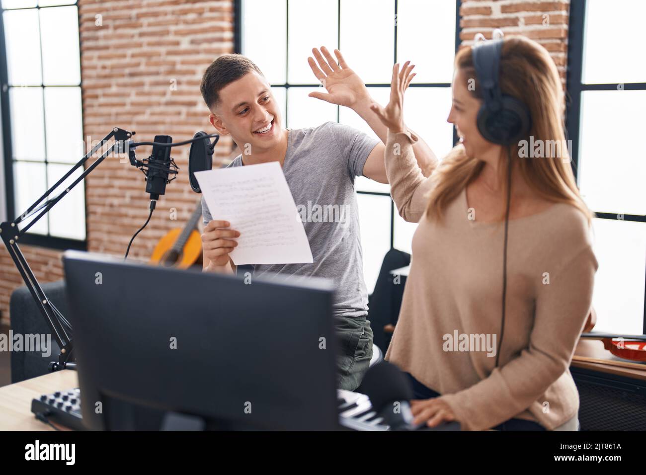 Man and woman musicians singing song high five with hands raised up at ...