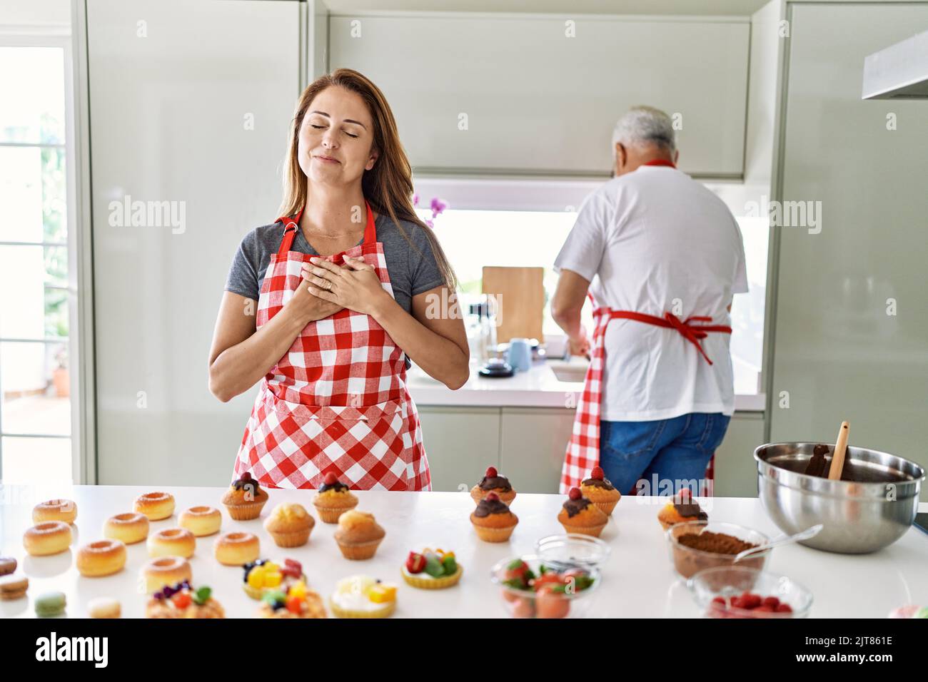 Middle age hispanic woman wearing apron cooking homemade pastries ...