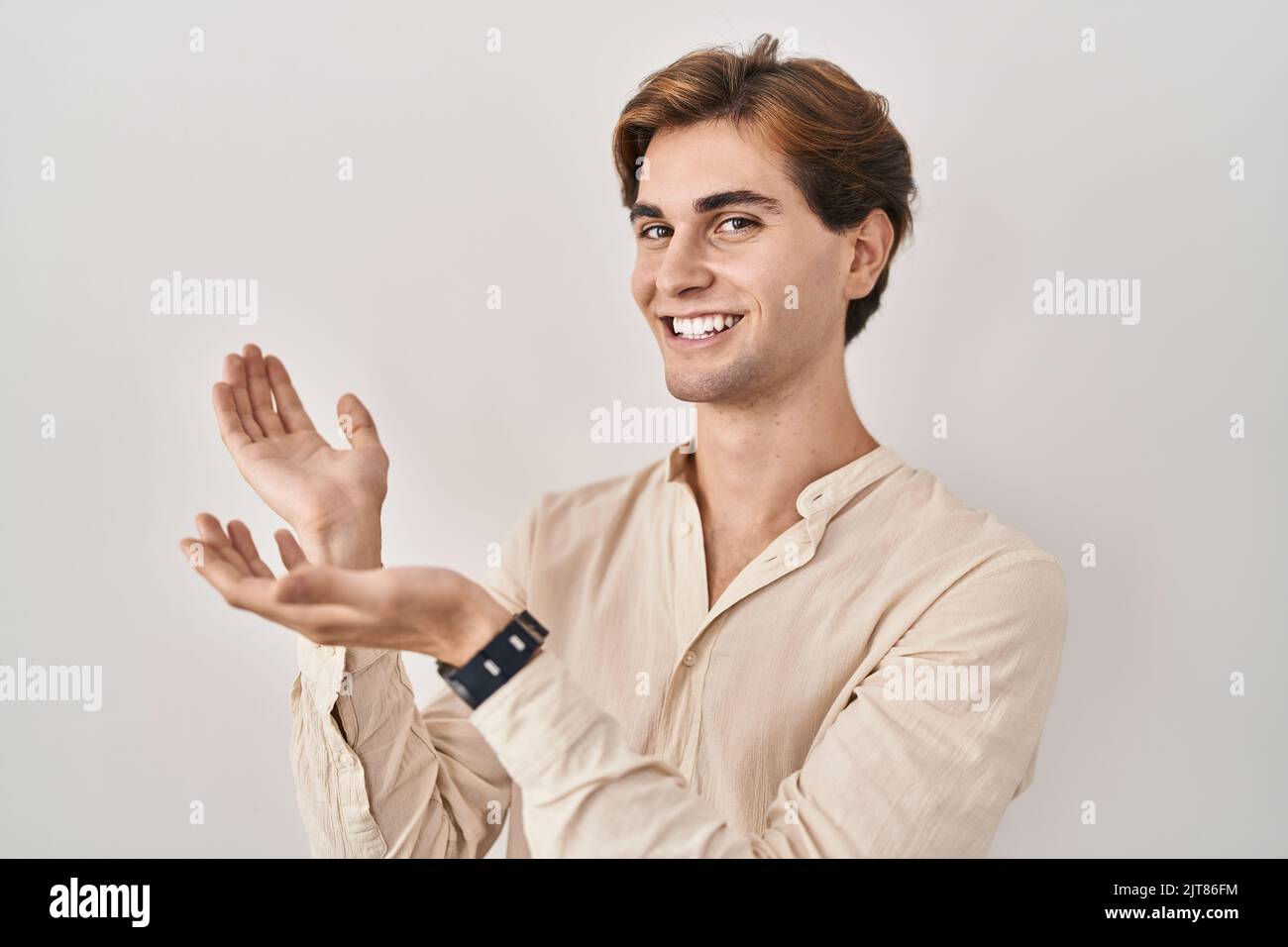 Young man standing over isolated background inviting to enter smiling ...