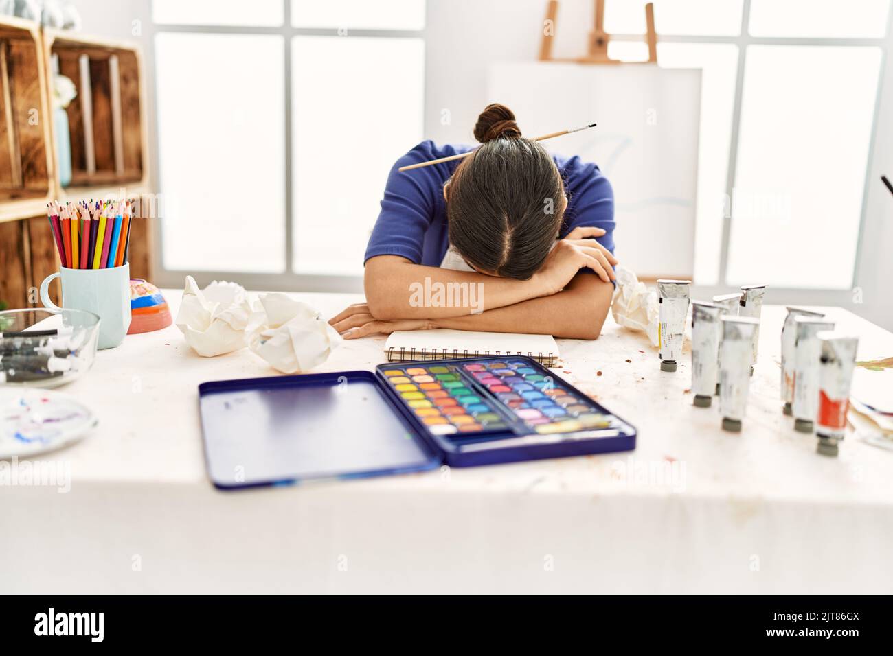 Young latin woman crying sitting on table at art studio Stock Photo - Alamy