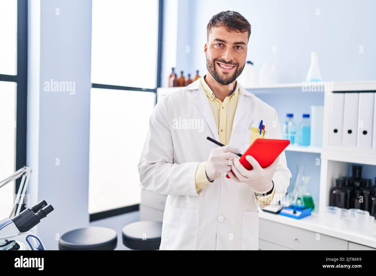 Young hispanic man wearing scientist uniform using touchpad at laboratory Stock Photo - Alamy