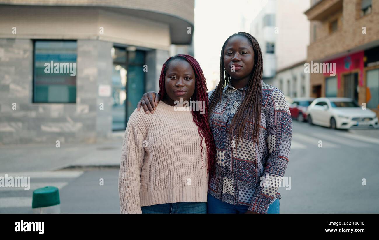 Two african american friends with serious expression hugging each other ...