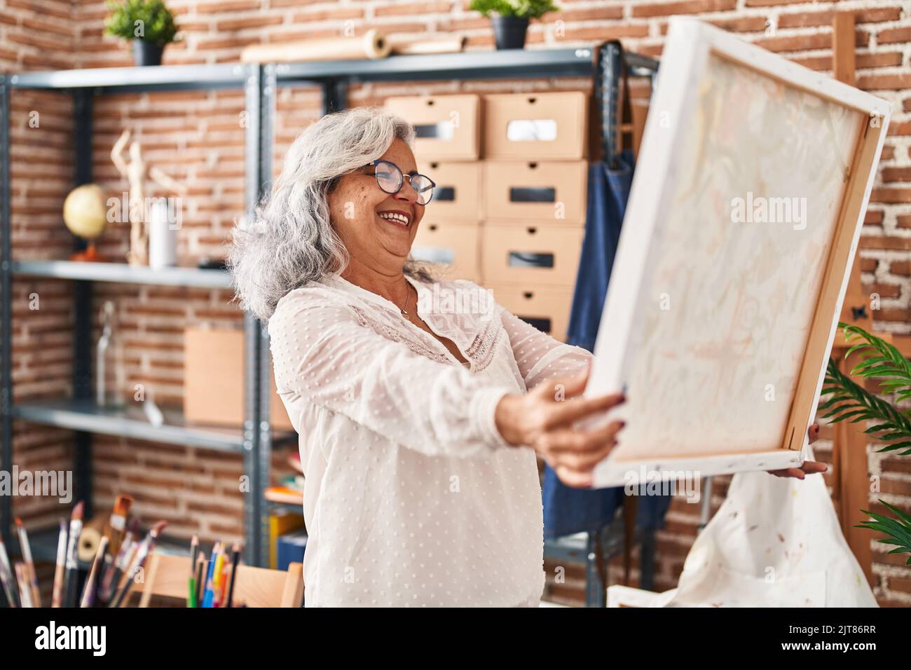 Middle age woman artist smiling confident looking draw at art studio ...