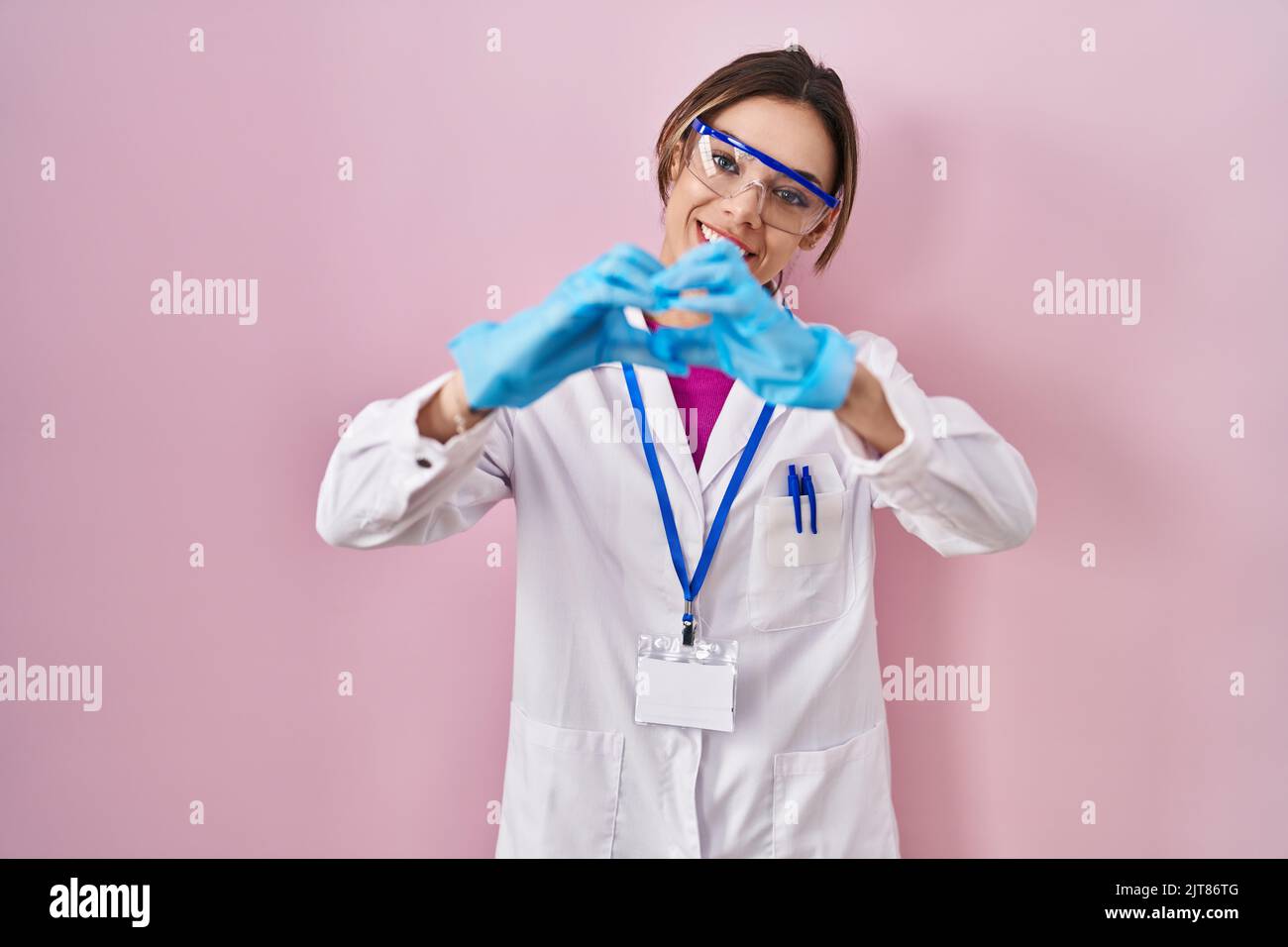 Hispanic woman wearing scientist uniform smiling in love showing heart ...