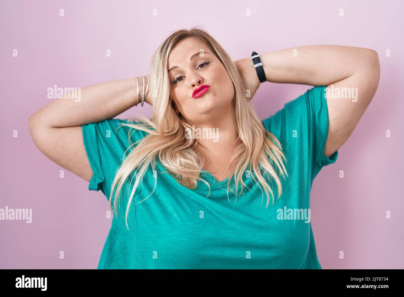 Caucasian plus size woman standing over pink background relaxing and ...