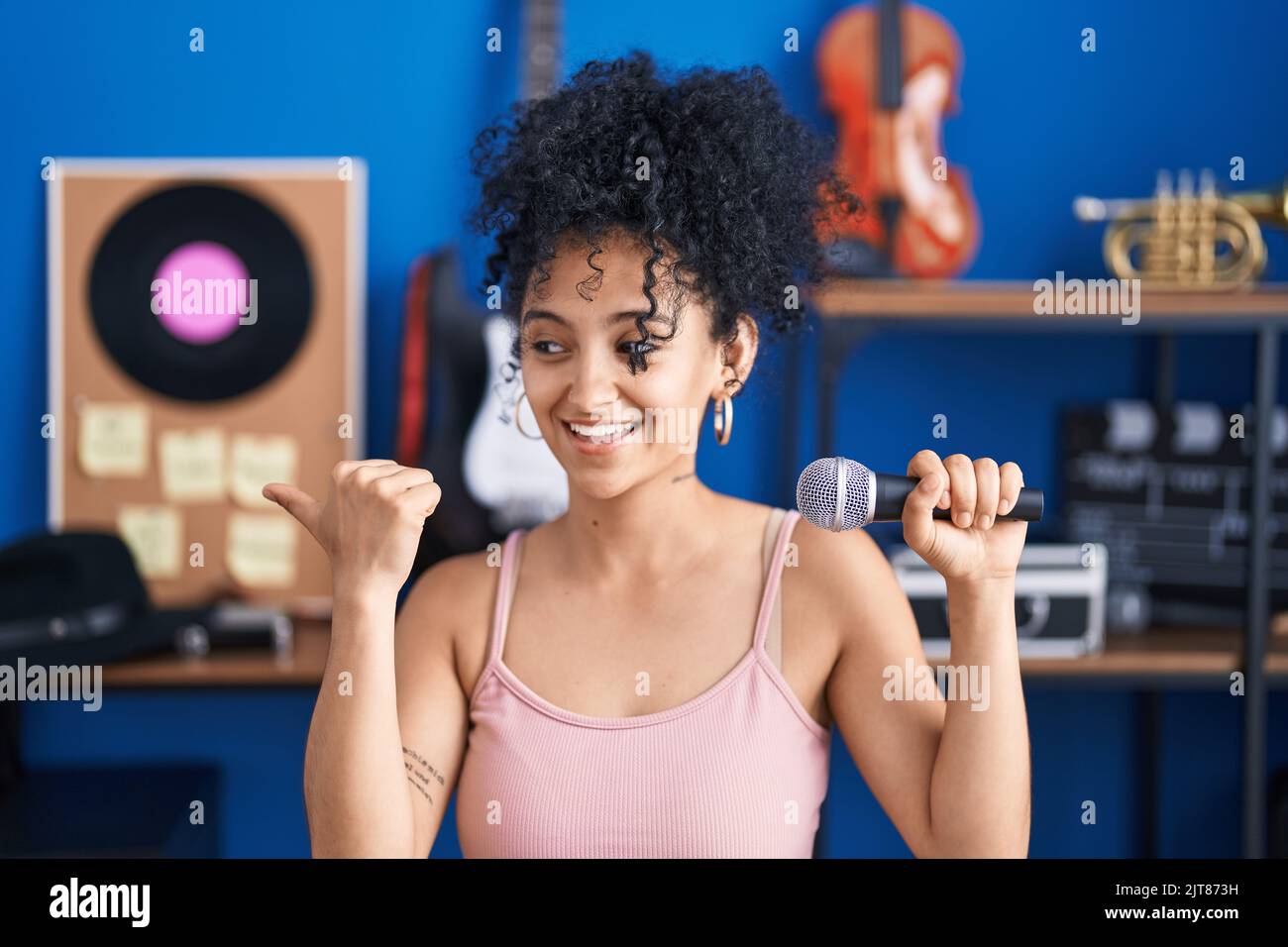 Hispanic woman with curly hair singing song using microphone at music ...