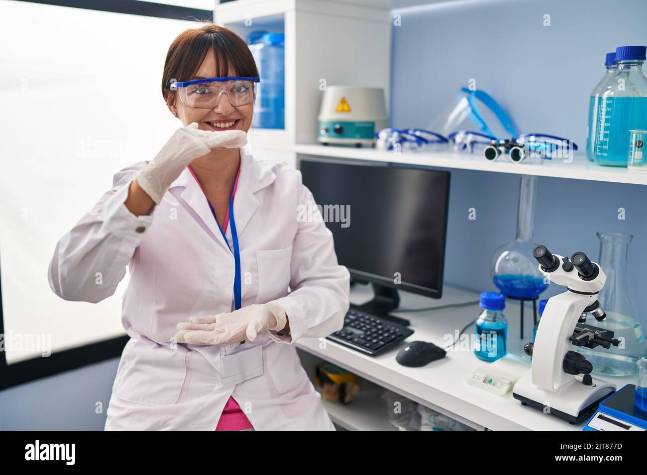 Young brunette woman working at scientist laboratory gesturing with ...