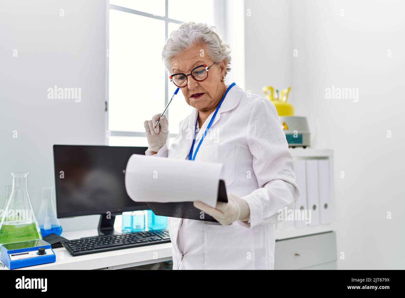 Senior grey-haired woman wearing scientist uniform with doubt ...