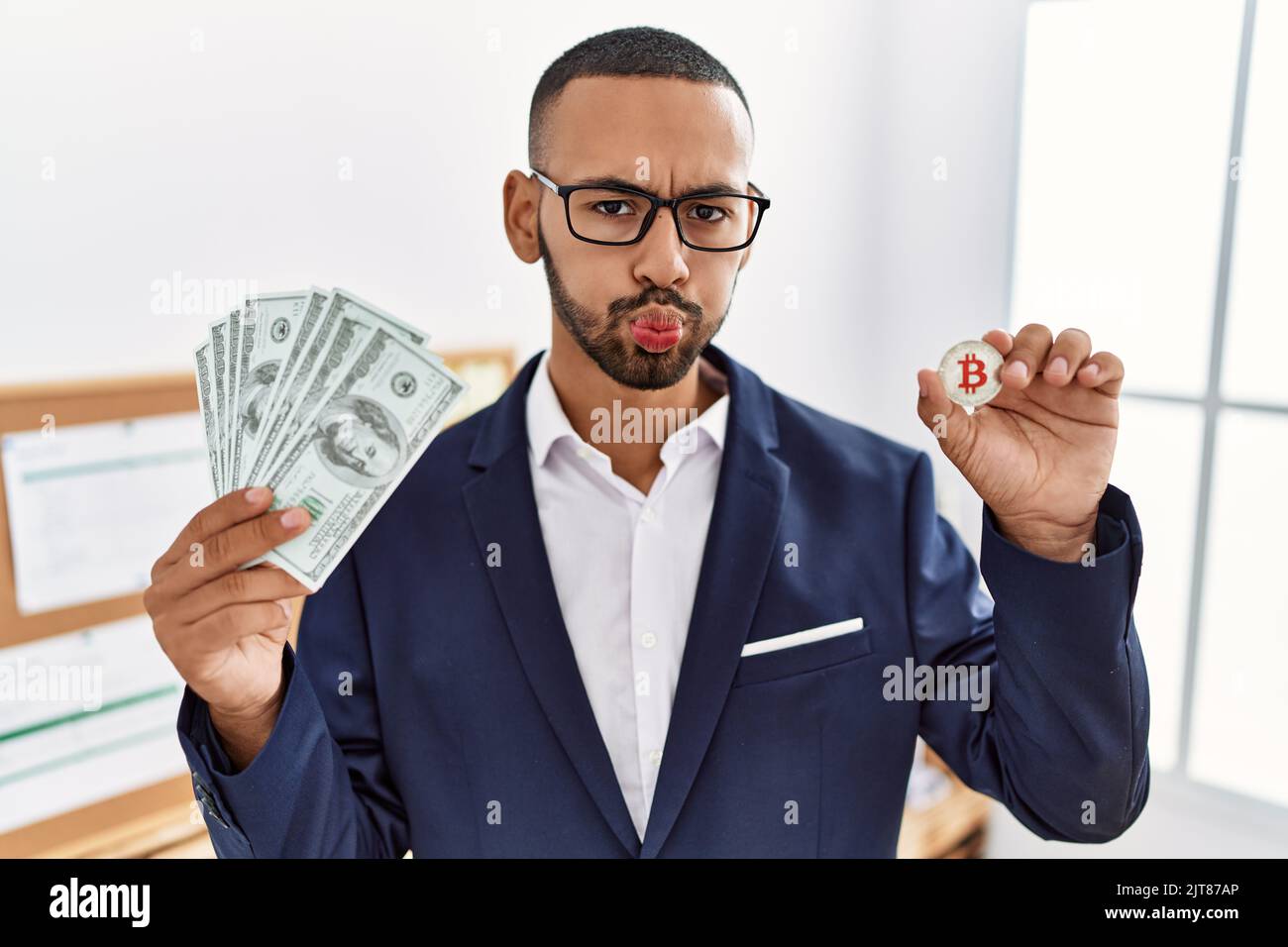 African american young man holding bitcoin virtual money and dollars ...