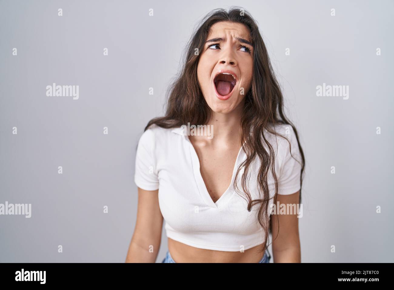 Young teenager girl standing over white background angry and mad ...