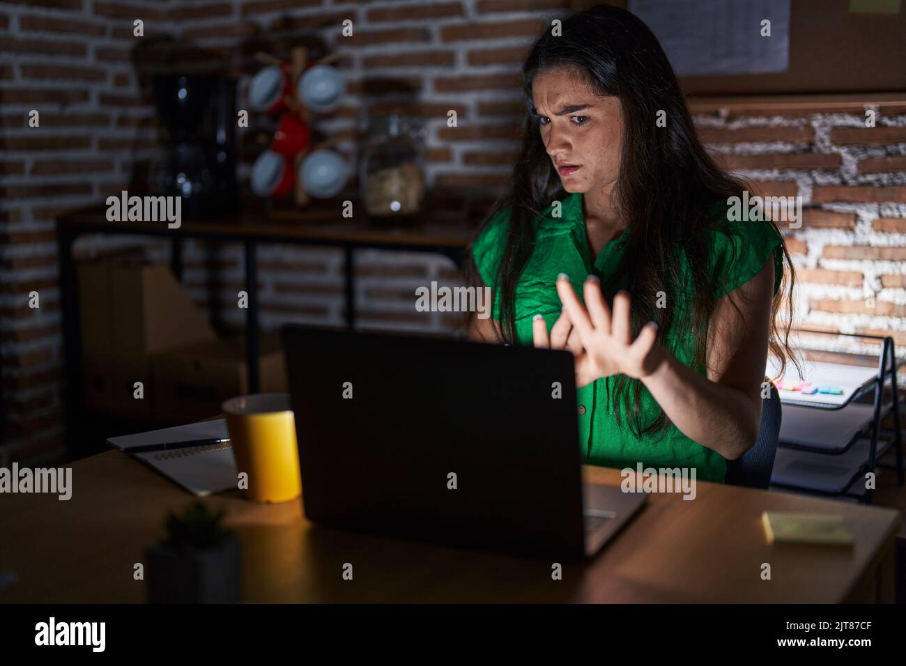 Young teenager girl working at the office at night disgusted expression ...