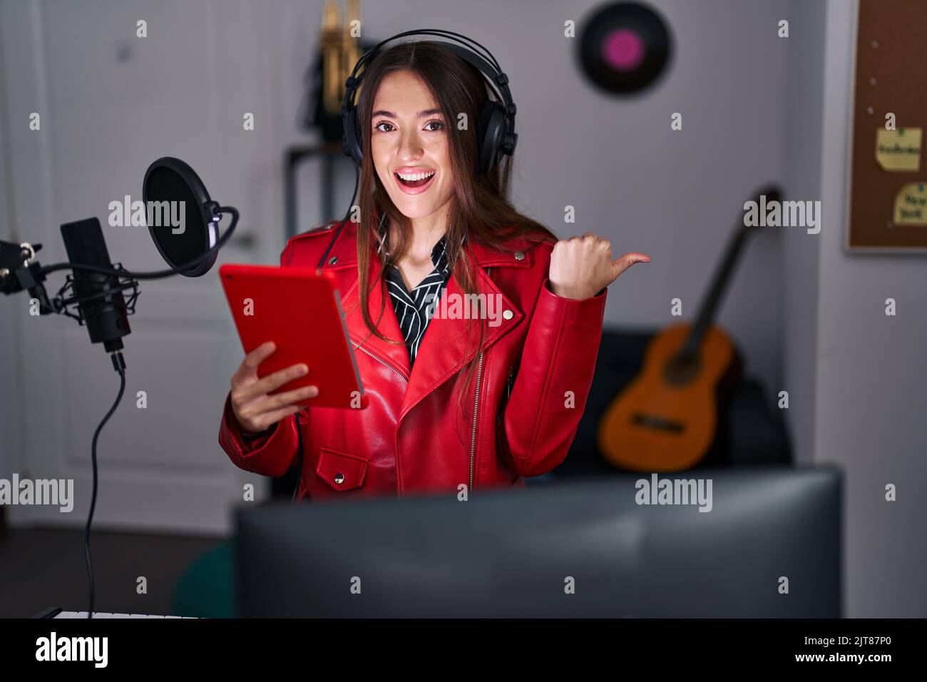 Young brunette woman singing song using microphone pointing thumb up to ...