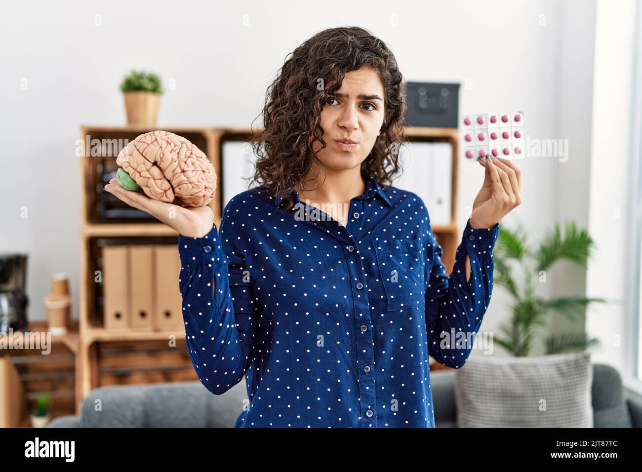 Young brunette woman holding brain and pills as mental health concept ...