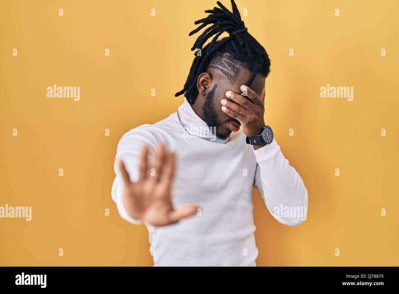 African man with dreadlocks wearing turtleneck sweater over yellow ...