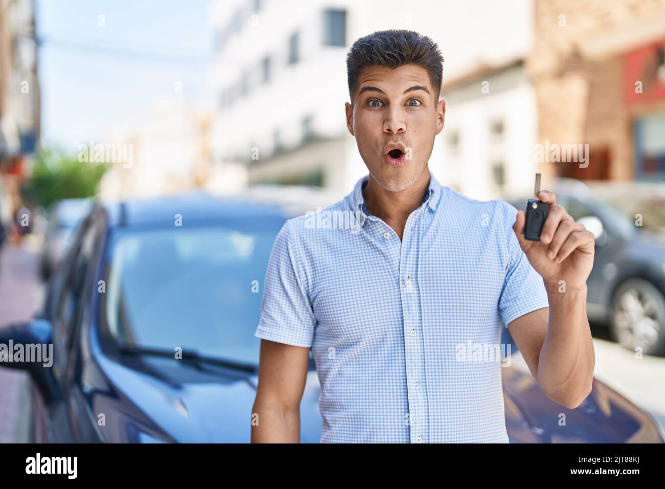 Young hispanic man holding car key scared and amazed with open mouth ...
