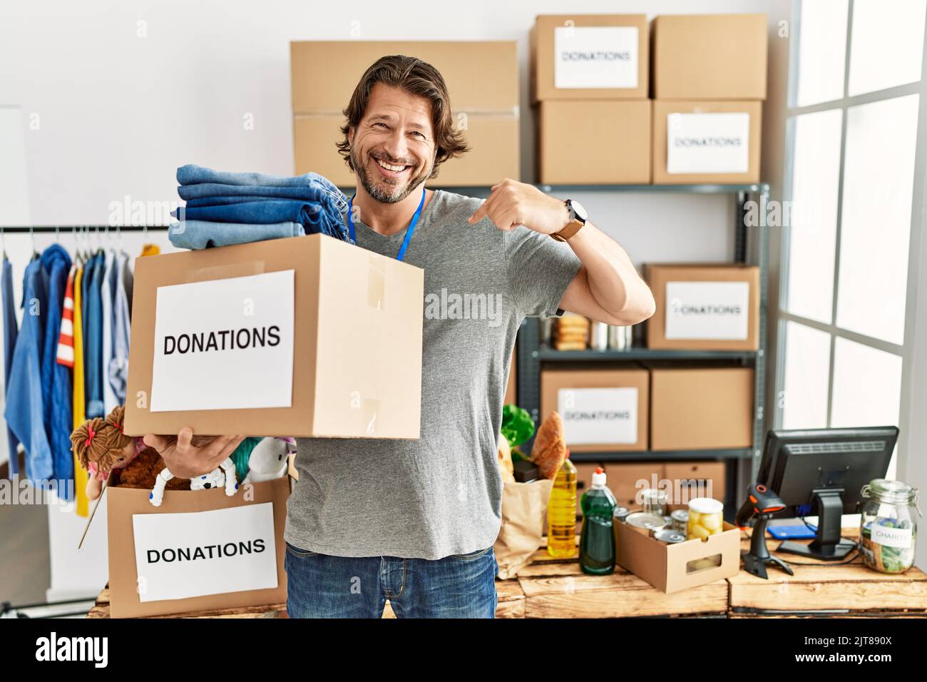 Handsome middle age man holding donations box for charity at volunteer ...