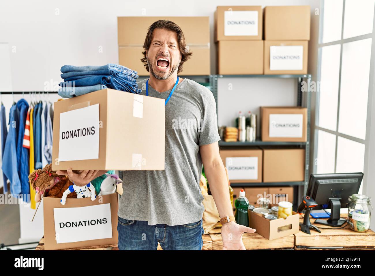 Handsome middle age man holding donations box for charity at volunteer ...