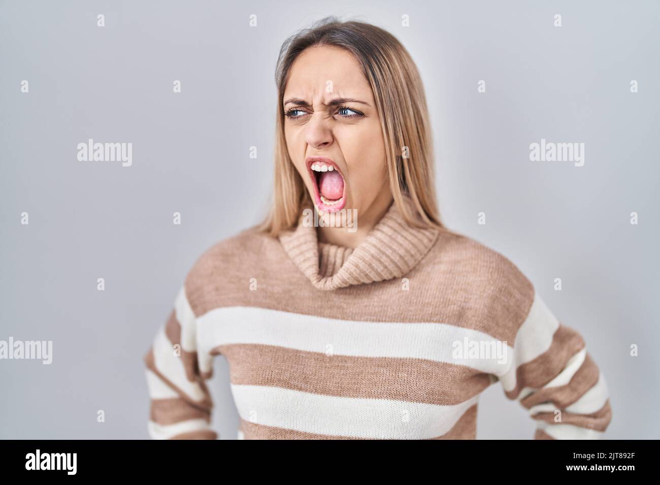 Young blonde woman wearing turtleneck sweater over isolated background ...