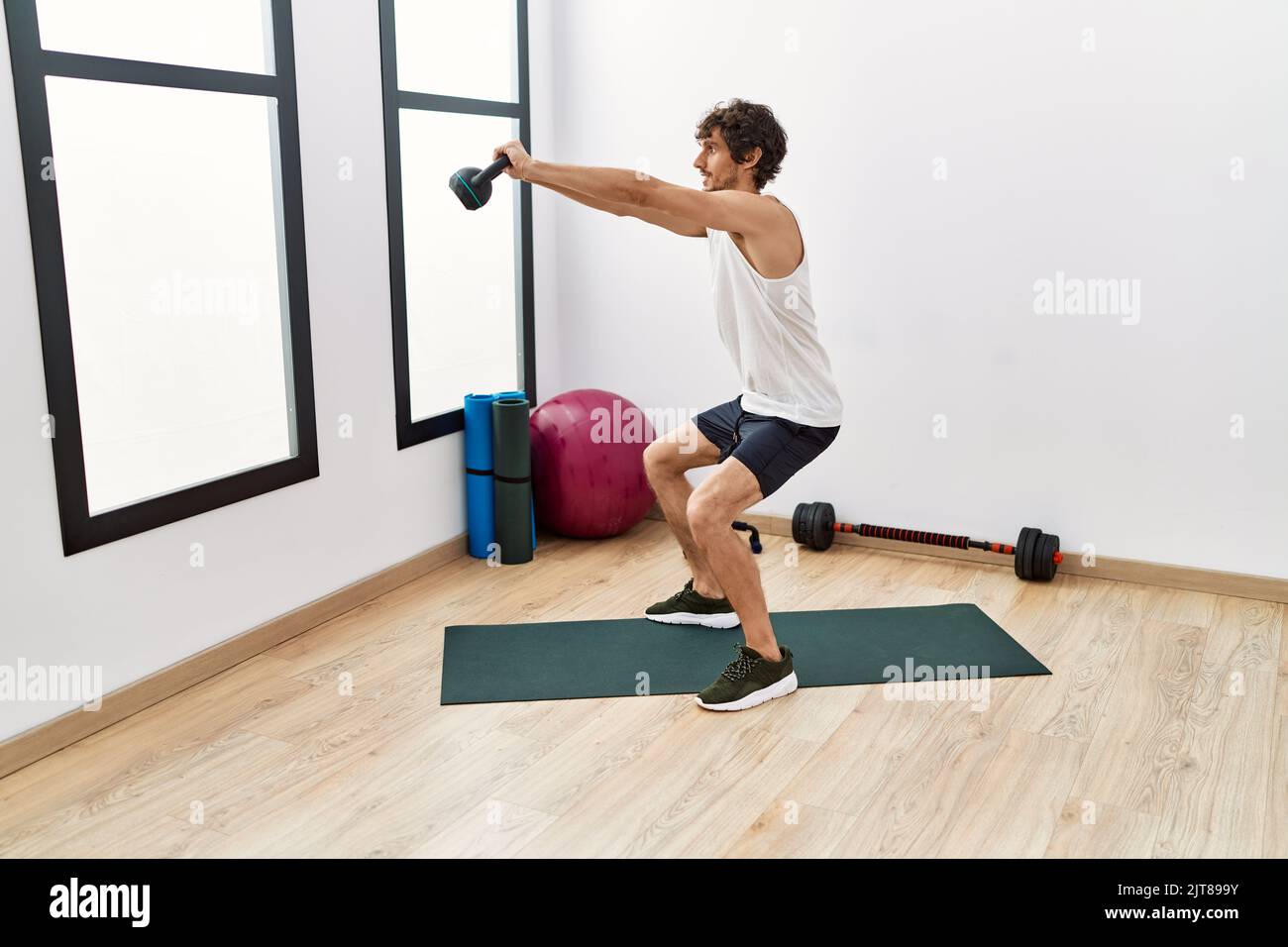 Young hispanic man smiling confident training using kettlebell at sport ...