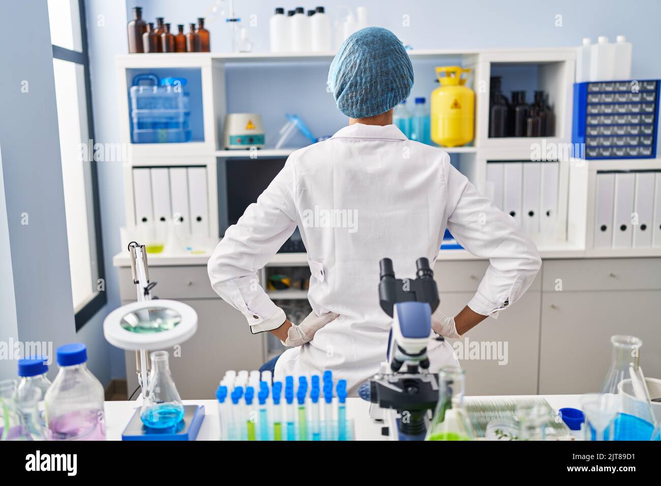 Brunette woman working at scientist laboratory standing backwards ...