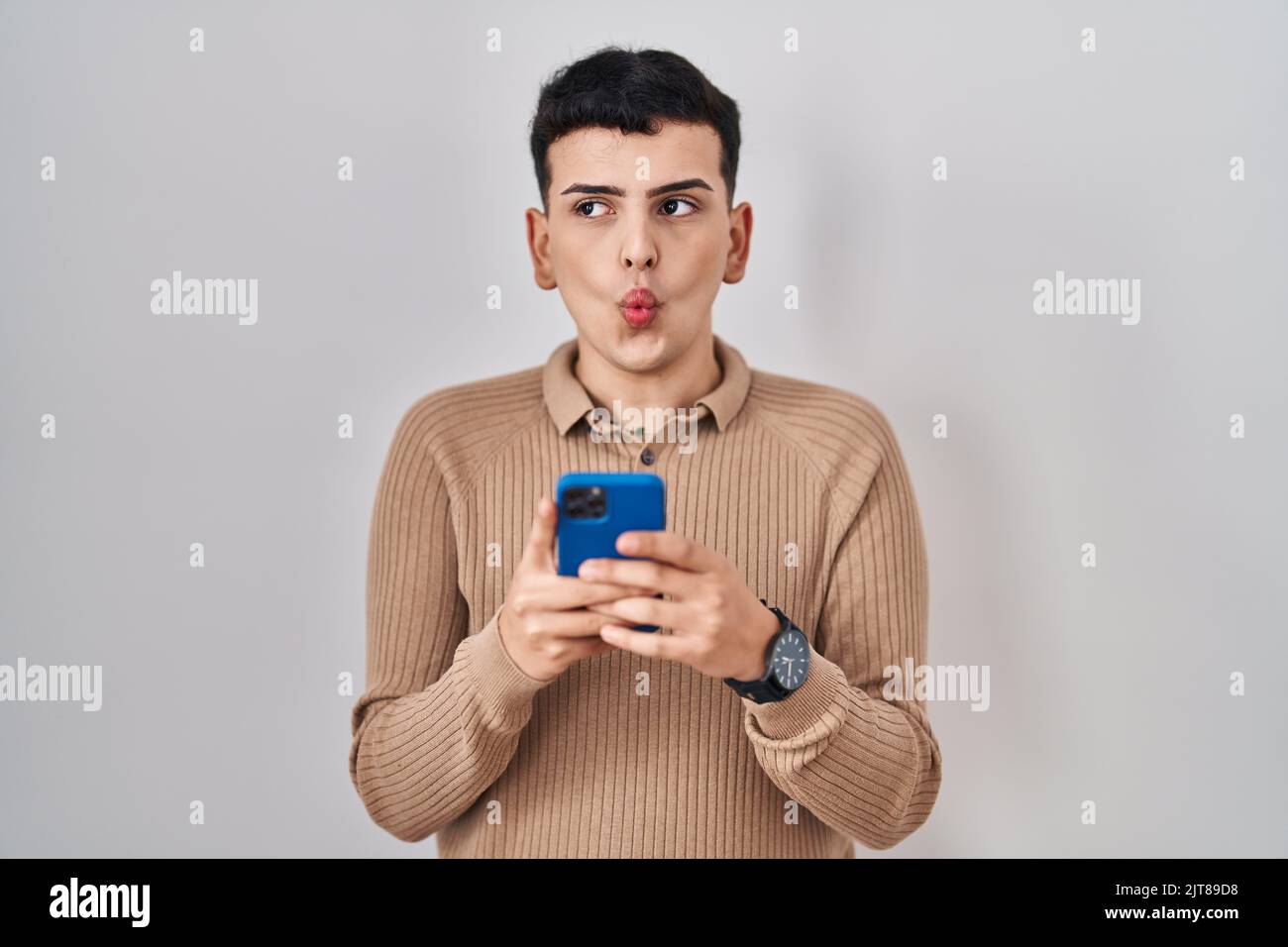 Non binary person using smartphone typing message making fish face with ...
