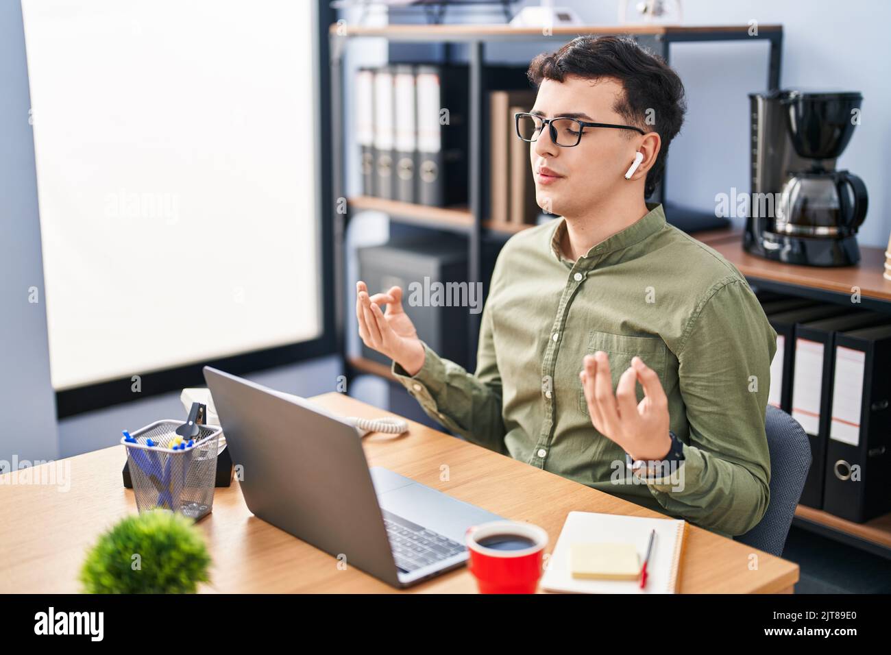 Young non binary man business worker doing yoga exercise at office ...