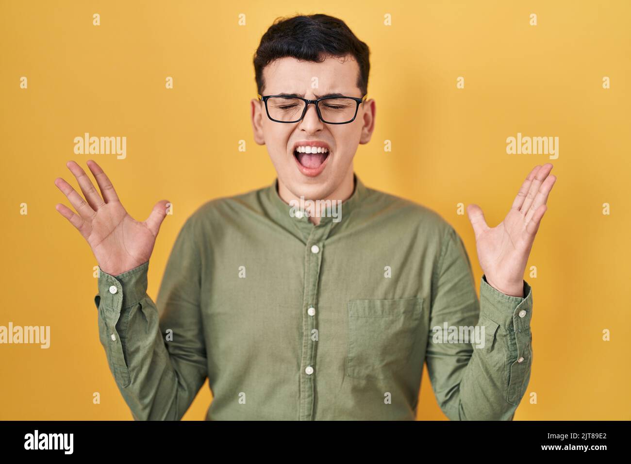 Non binary person standing over yellow background celebrating mad and ...