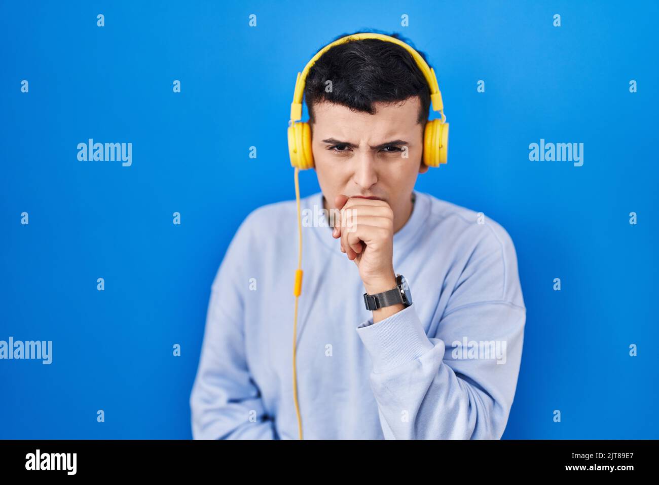 Non binary person listening to music using headphones feeling unwell ...