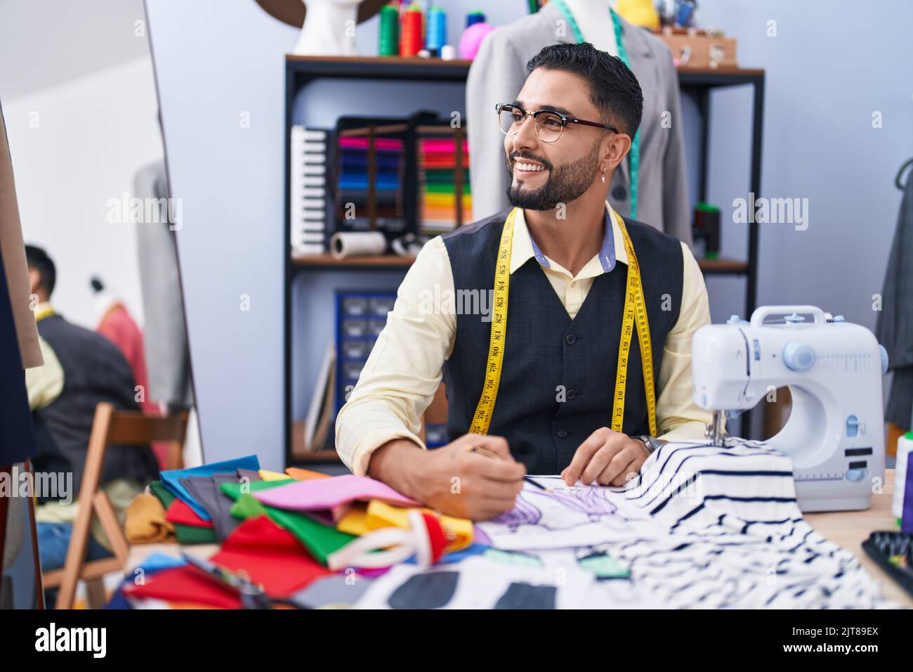 Young arab man tailor smiling confident drawing on notebook at clothing ...
