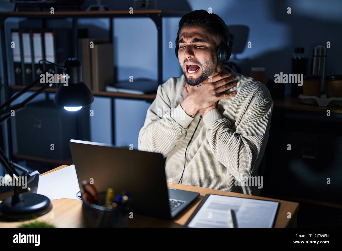 Young handsome man working using computer laptop at night shouting and ...