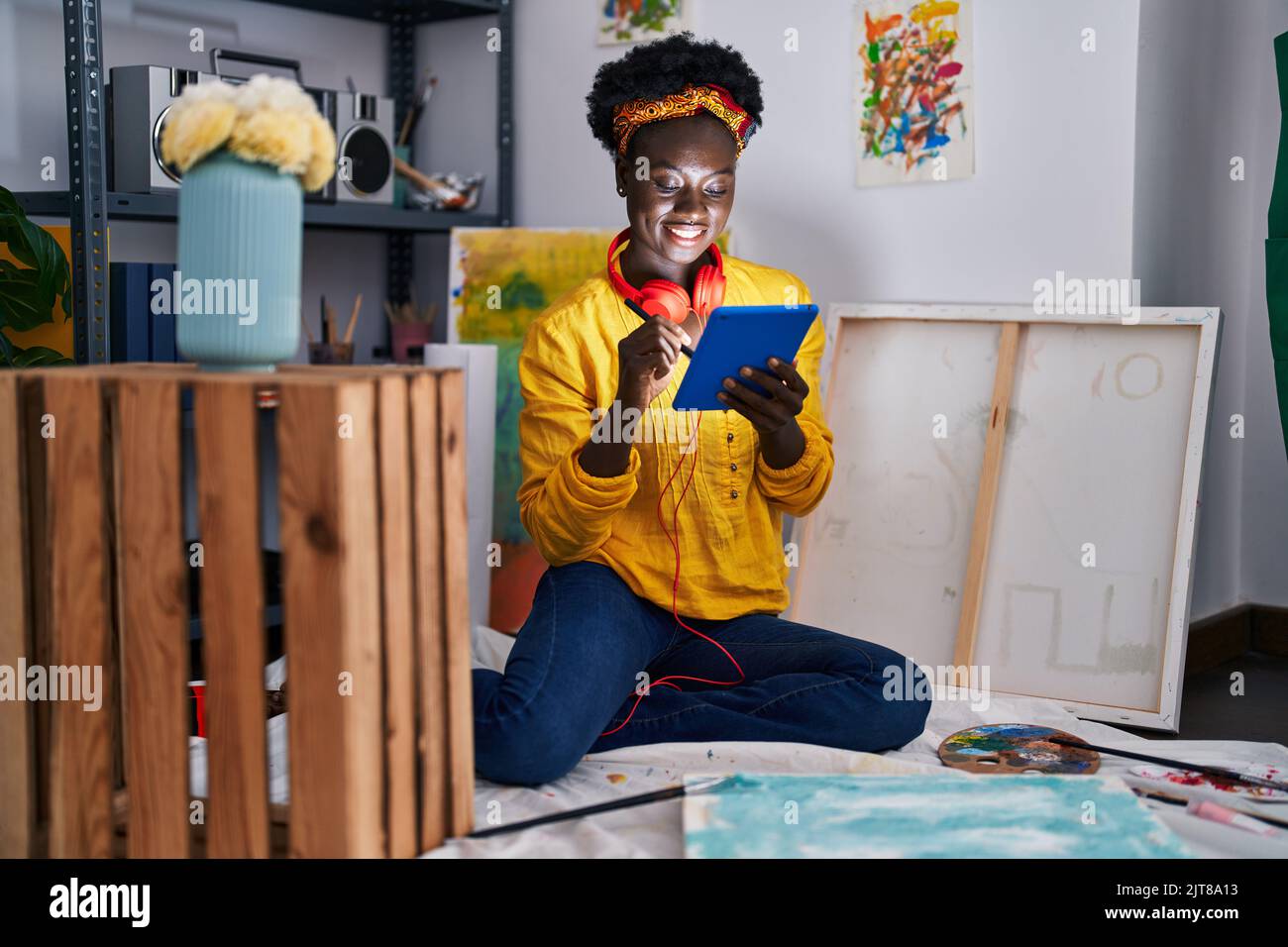 Young african american woman artist wearing headphones using touchpad ...
