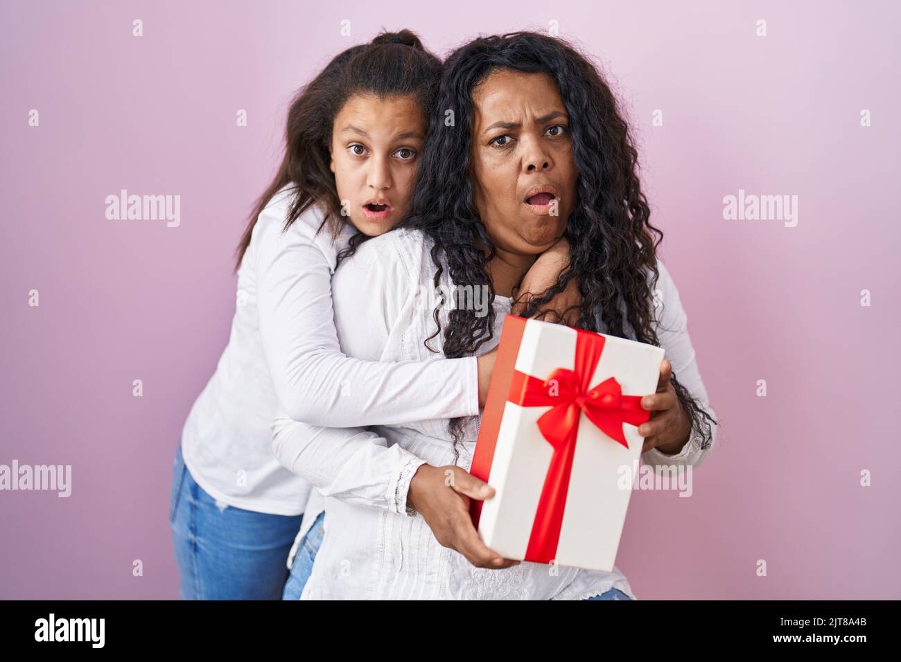 Mother and young daughter holding with presents in shock face, looking ...