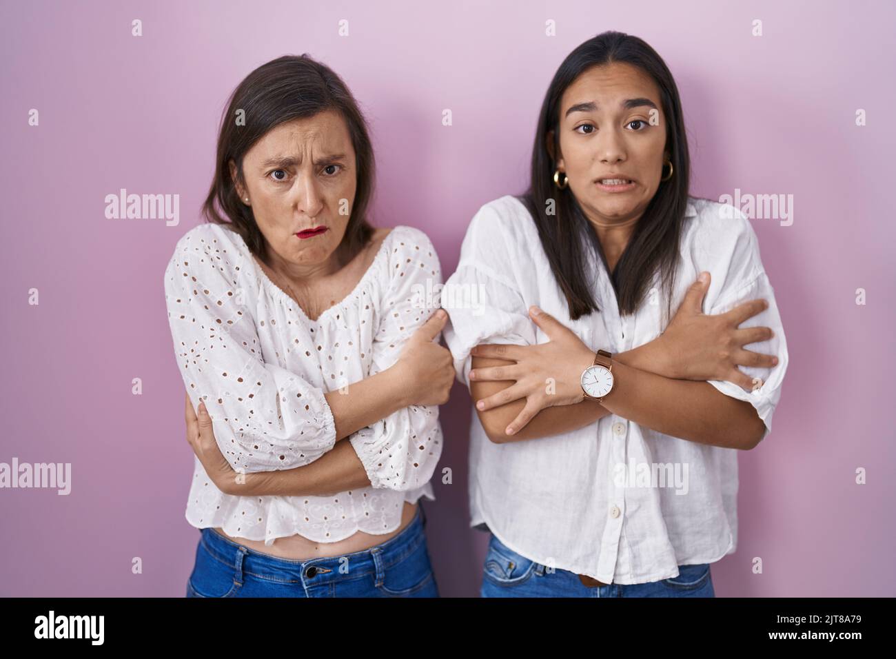 Hispanic mother and daughter together shaking and freezing for winter ...