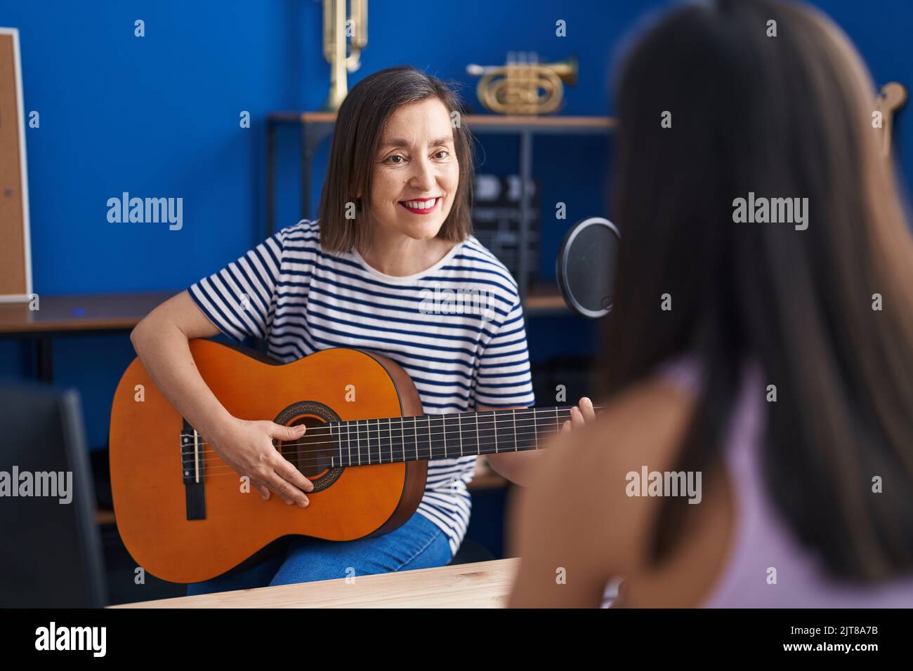 Two women musicians playing classical guitar and piano at music studio ...